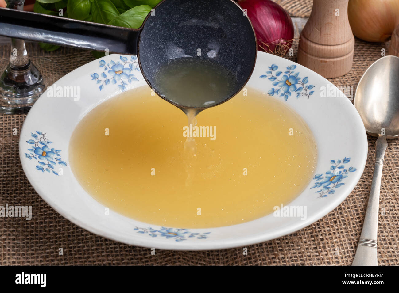 Chicken bone broth served in a white plate with a ladle Stock Photo - Alamy