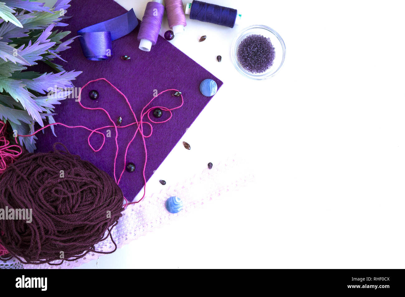 Materials for needlework in violet color on a white background. Beads ...