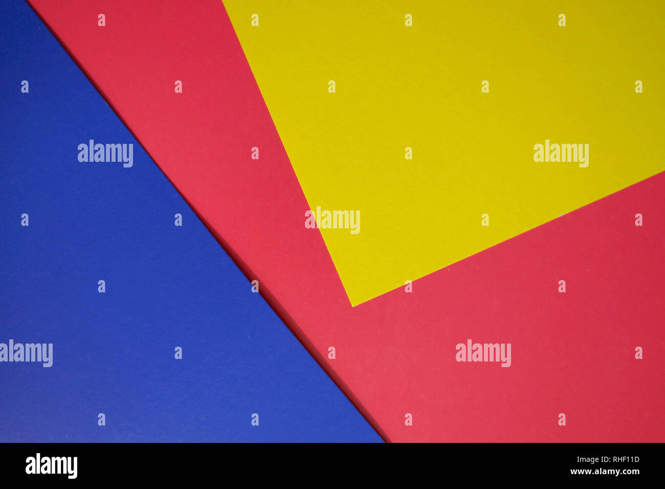 Bright flat lay background with color paper sheets. Yellow, blue and ...