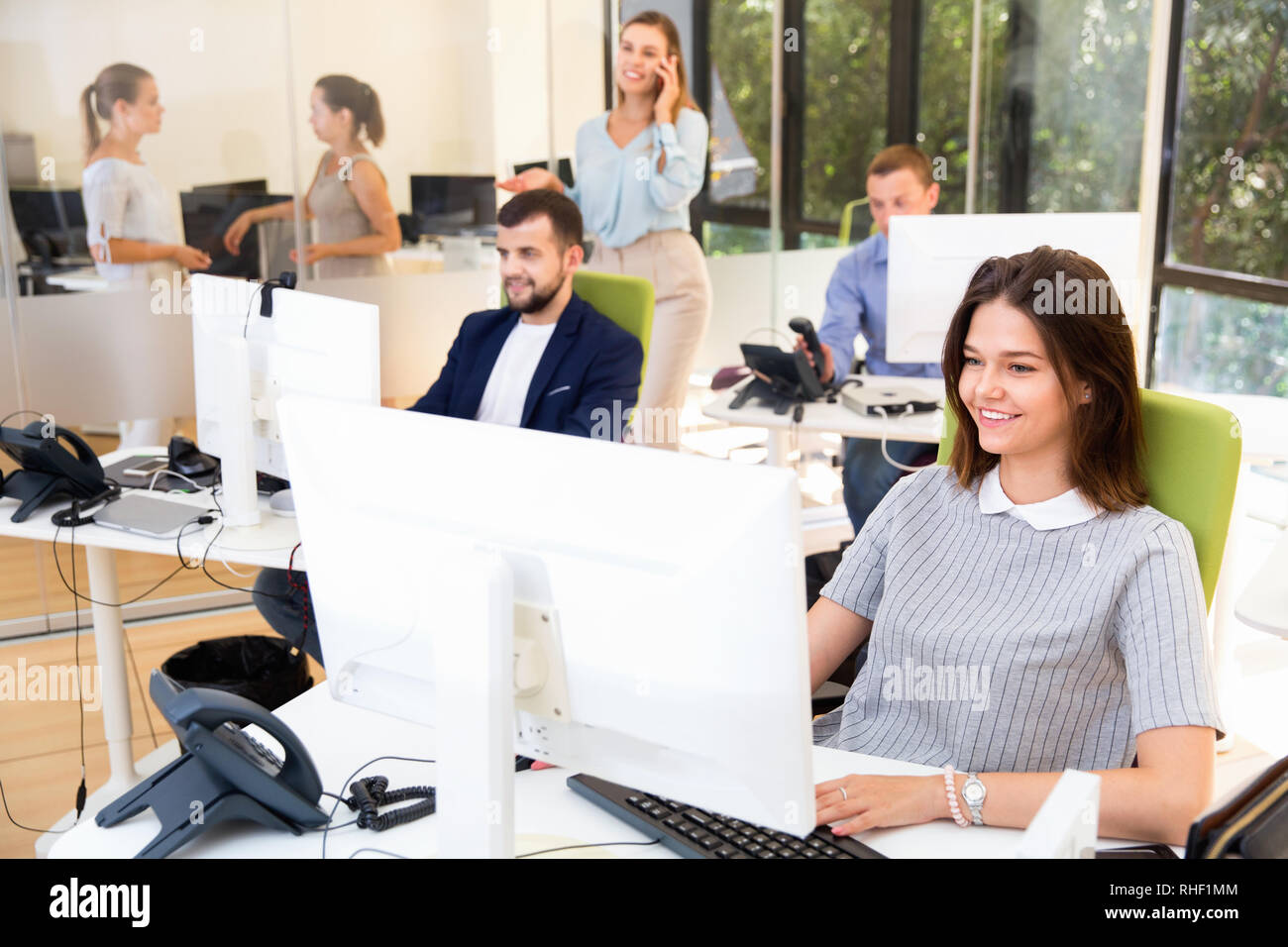 Group of diligent positive cheerful business people during daily work in modern co-working space ...