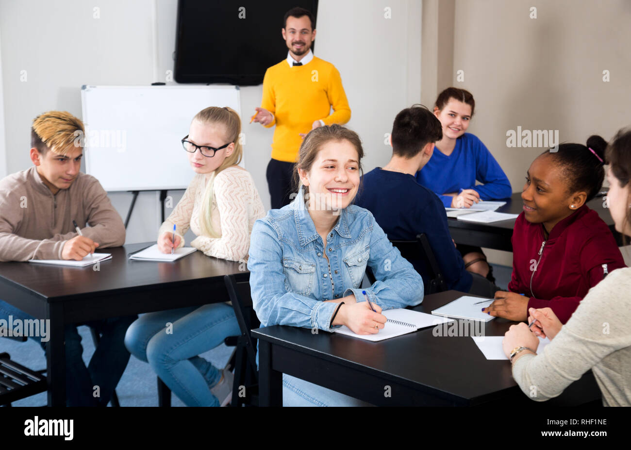 Young classmates and teacher working in groups to complete task during ...