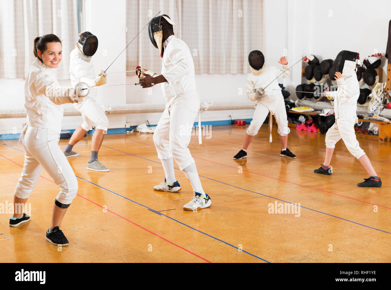 Young positive woman training attack movements with rapier at fencing ...