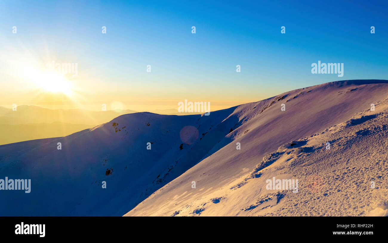 Sunset in the winter snowy mountains. Direct sunlight. Sun beam. Light ...