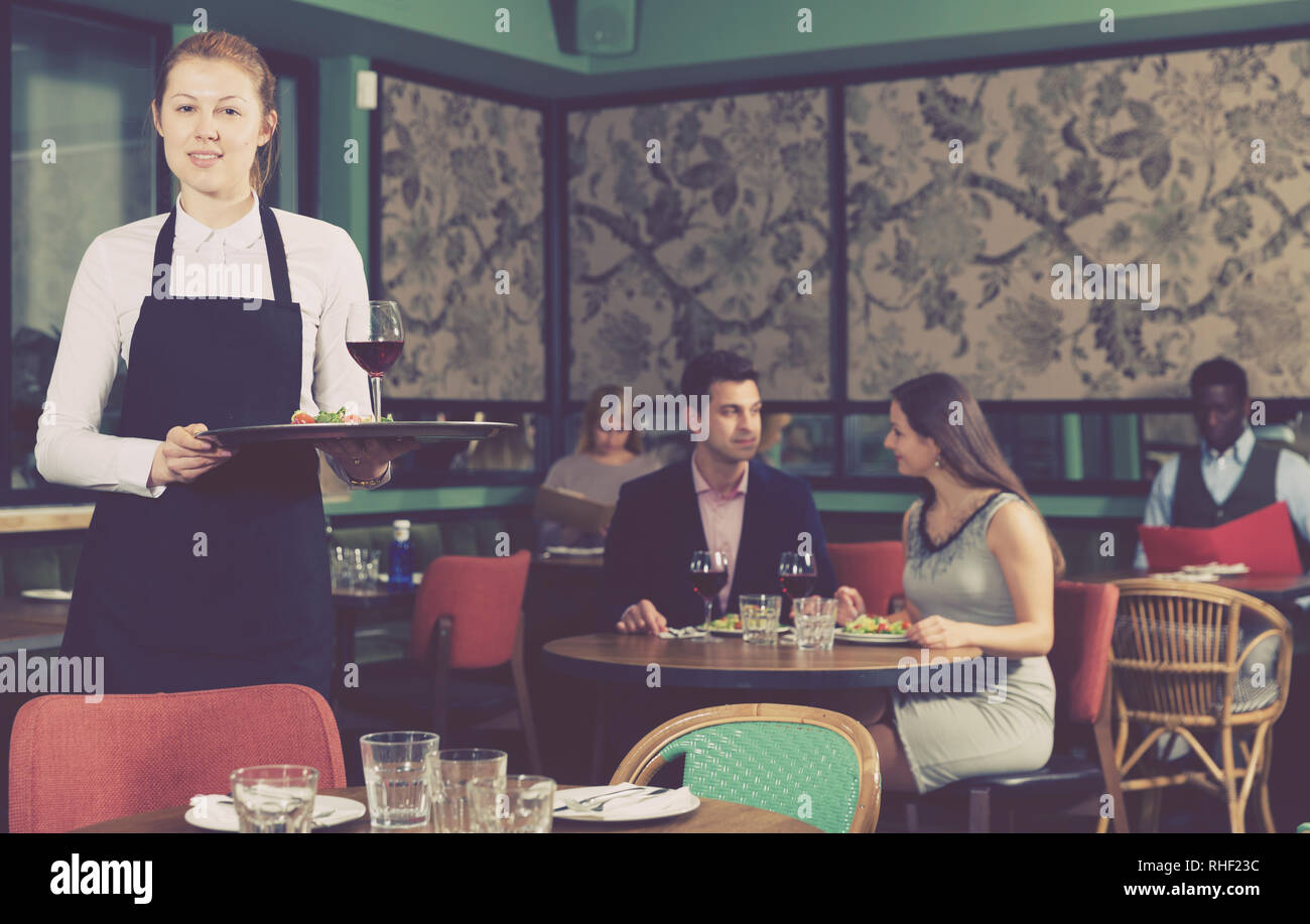 Attractive young waitress with serving tray welcoming in restaurant ...