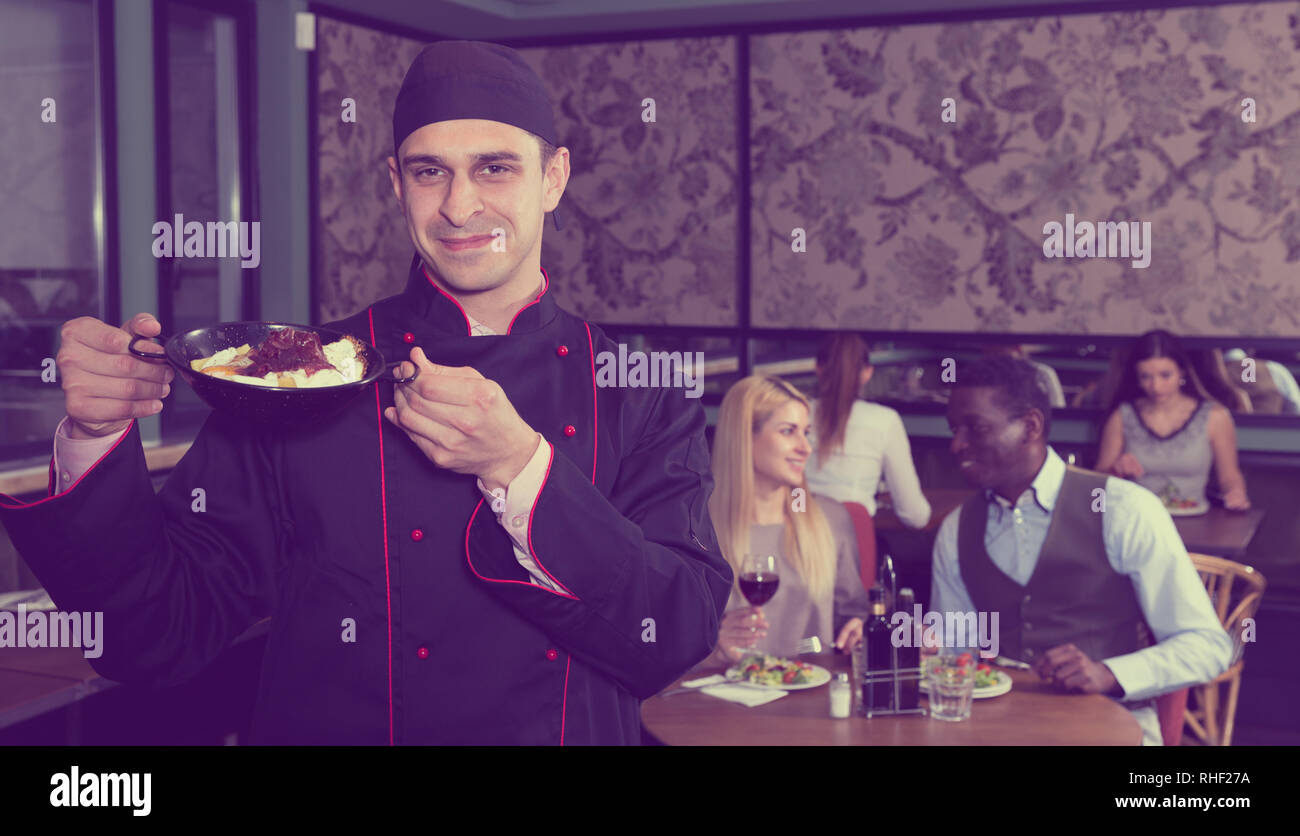 Proud male chef offering delicious dish for tasting in cosy restaurant ...