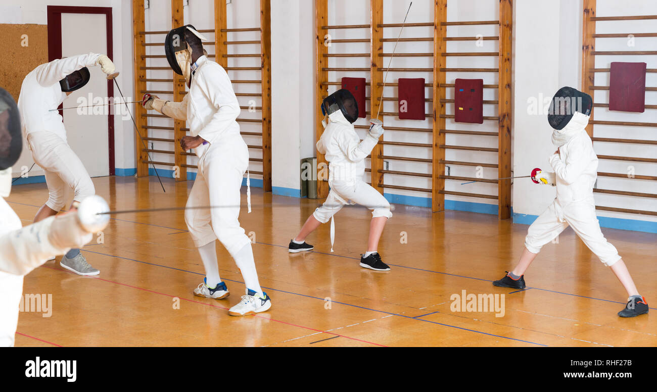 Group of kids and adults fencers with instructor engaged in fencing in ...