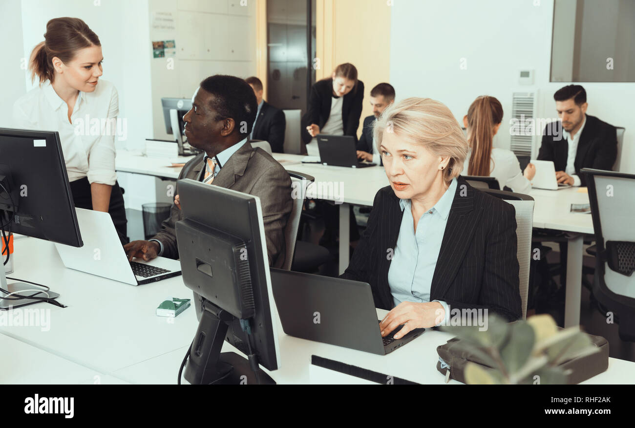 Successful coworkers engaged in business activities in busy open plan ...