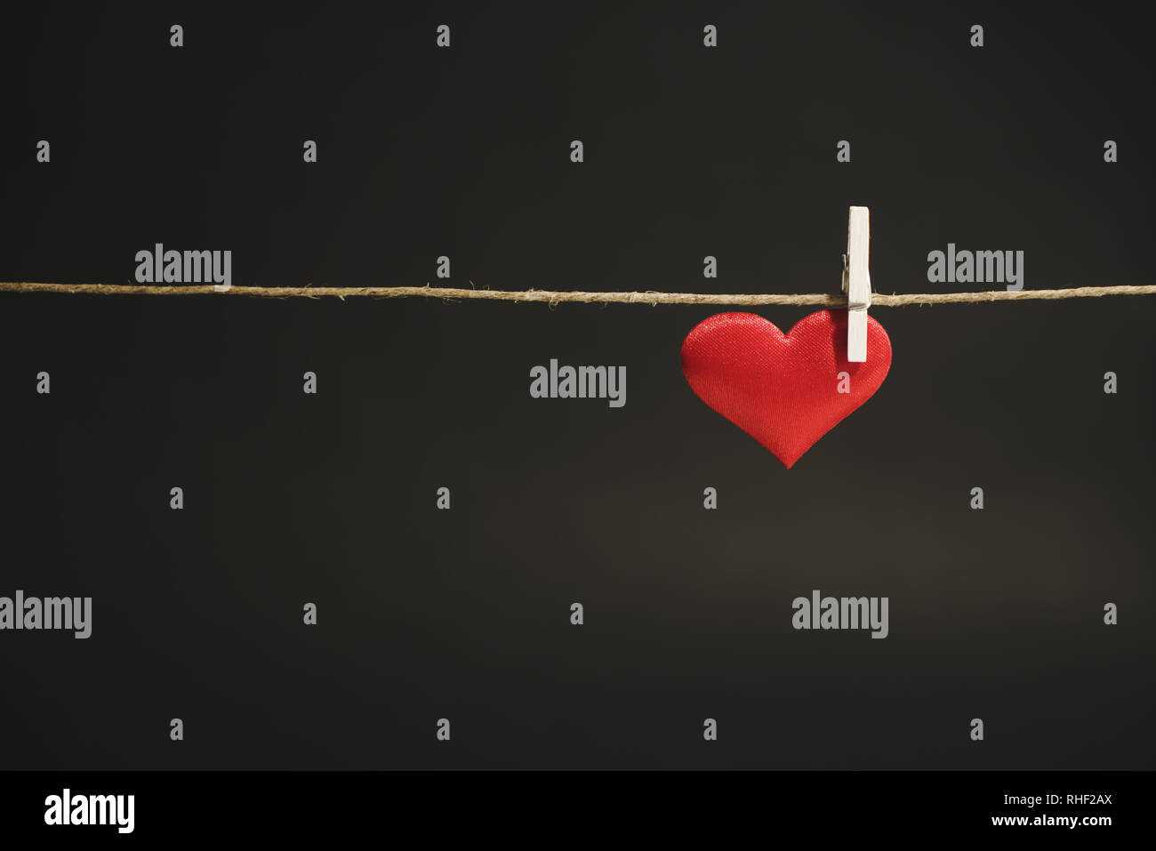 A single adorable red heart hanging from a string by white clothes peg ...