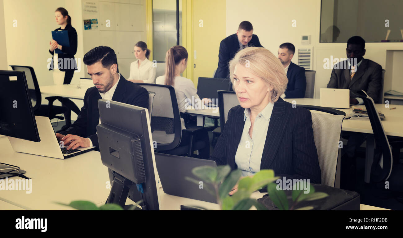 Successful coworkers engaged in business activities in busy open plan ...