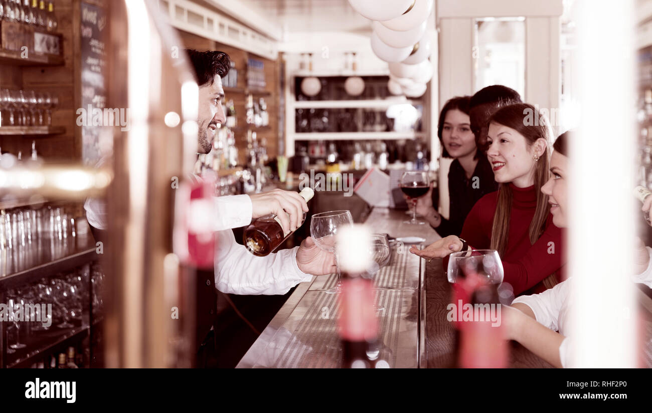 Young people sitting on bar in restaurant, ordering drinks to smiling ...