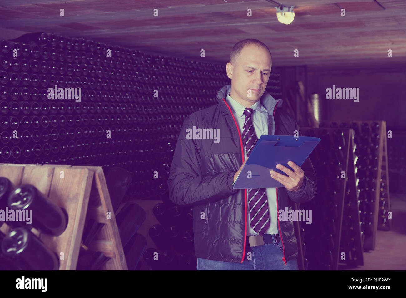 Confident male winemaker working in wine cellar, taking notes on ...