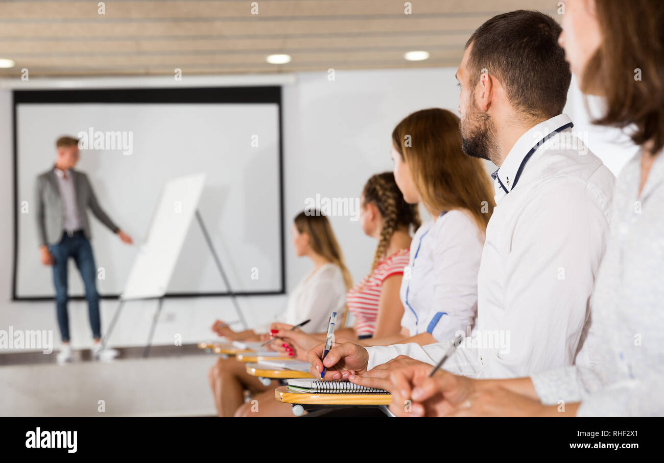 Side view of student group working on lecture in classroom, making ...
