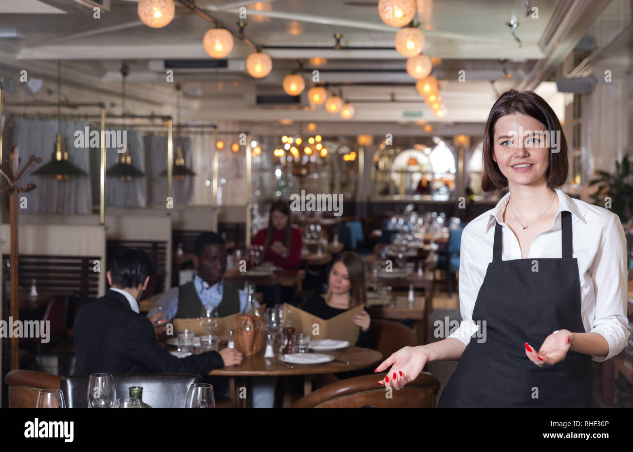 Woman waiter is welcoming clients in hall of luxurious restaurant Stock ...