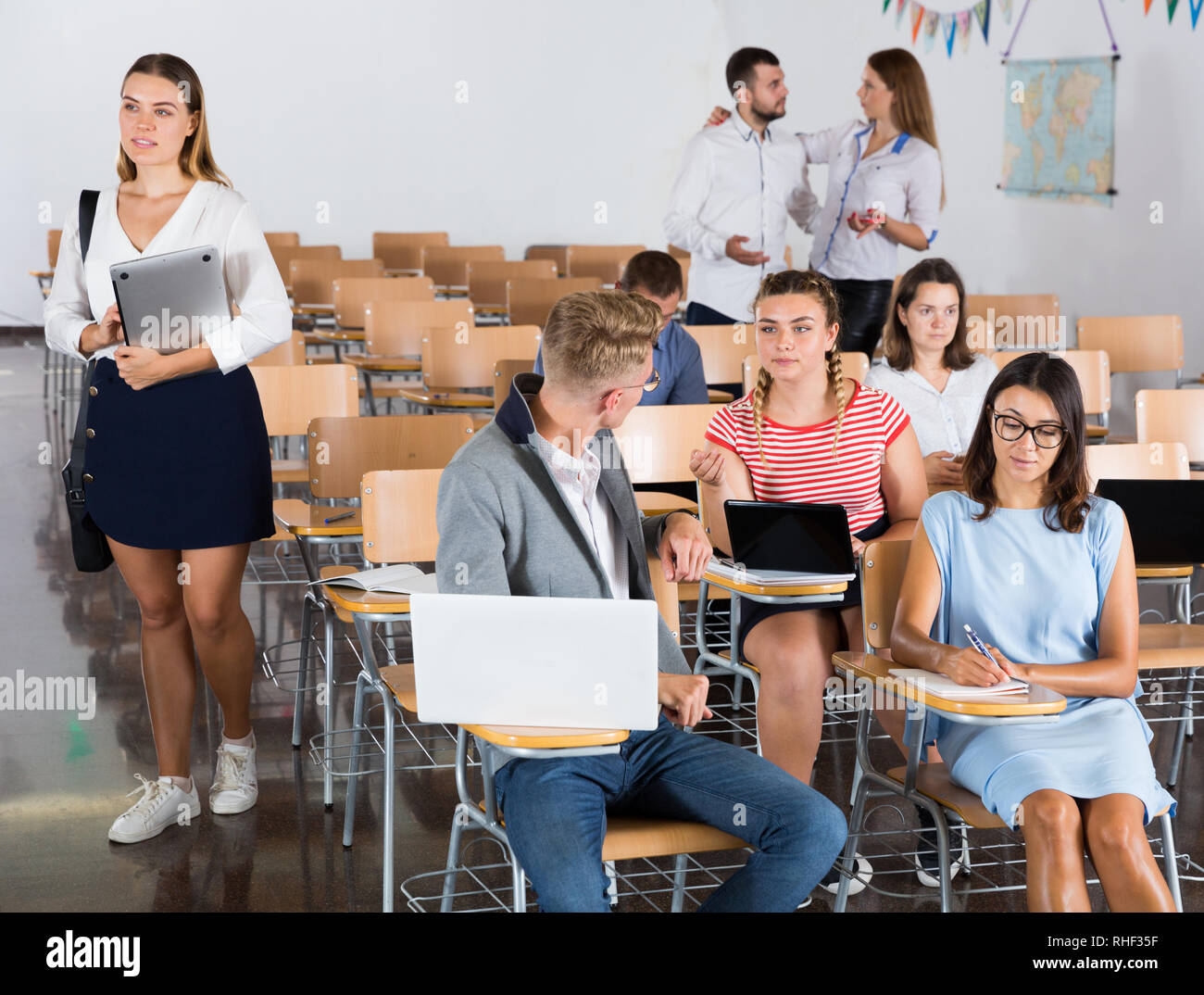 Happy group of adult students lively chatting while enjoying free time ...