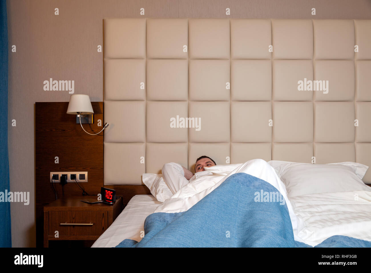 Man chef lies in bed under blanket in uniform in hotel room. Concept ...