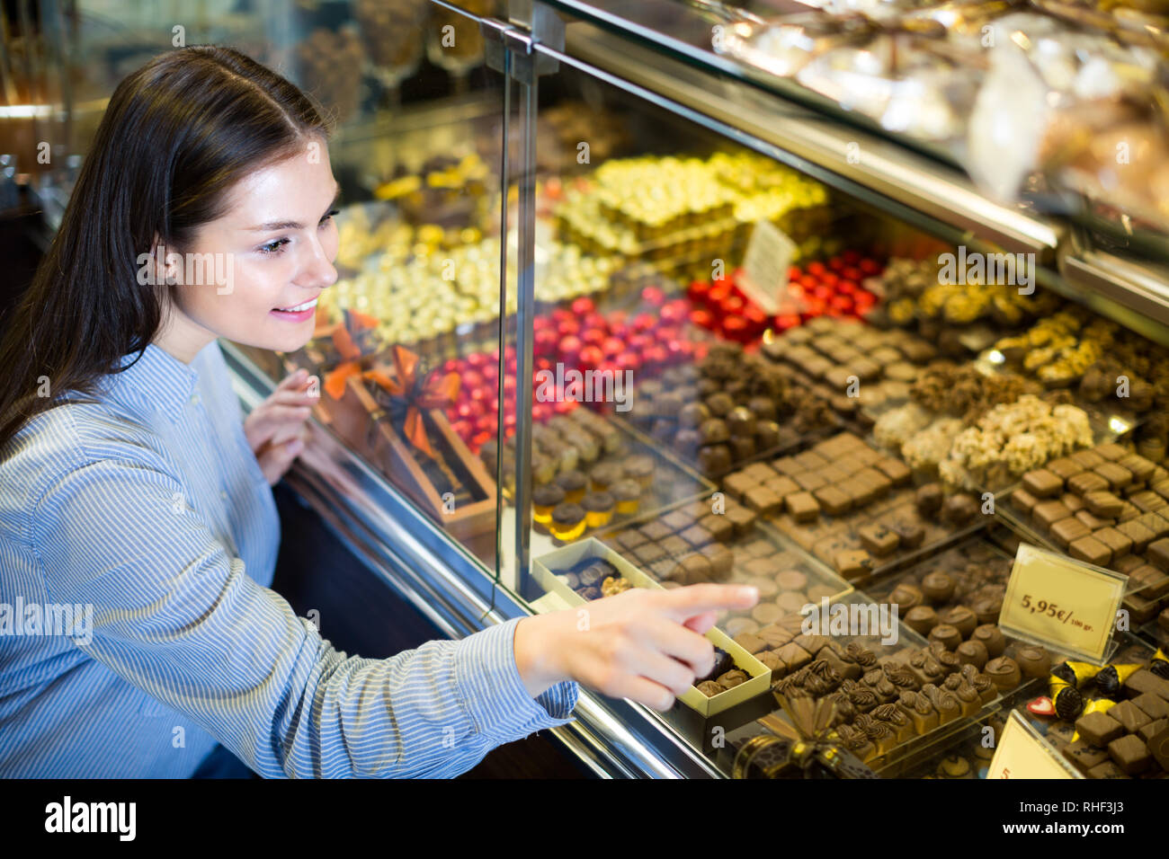 happy woman selecting fine chocolates and confectionery at cafe display ...