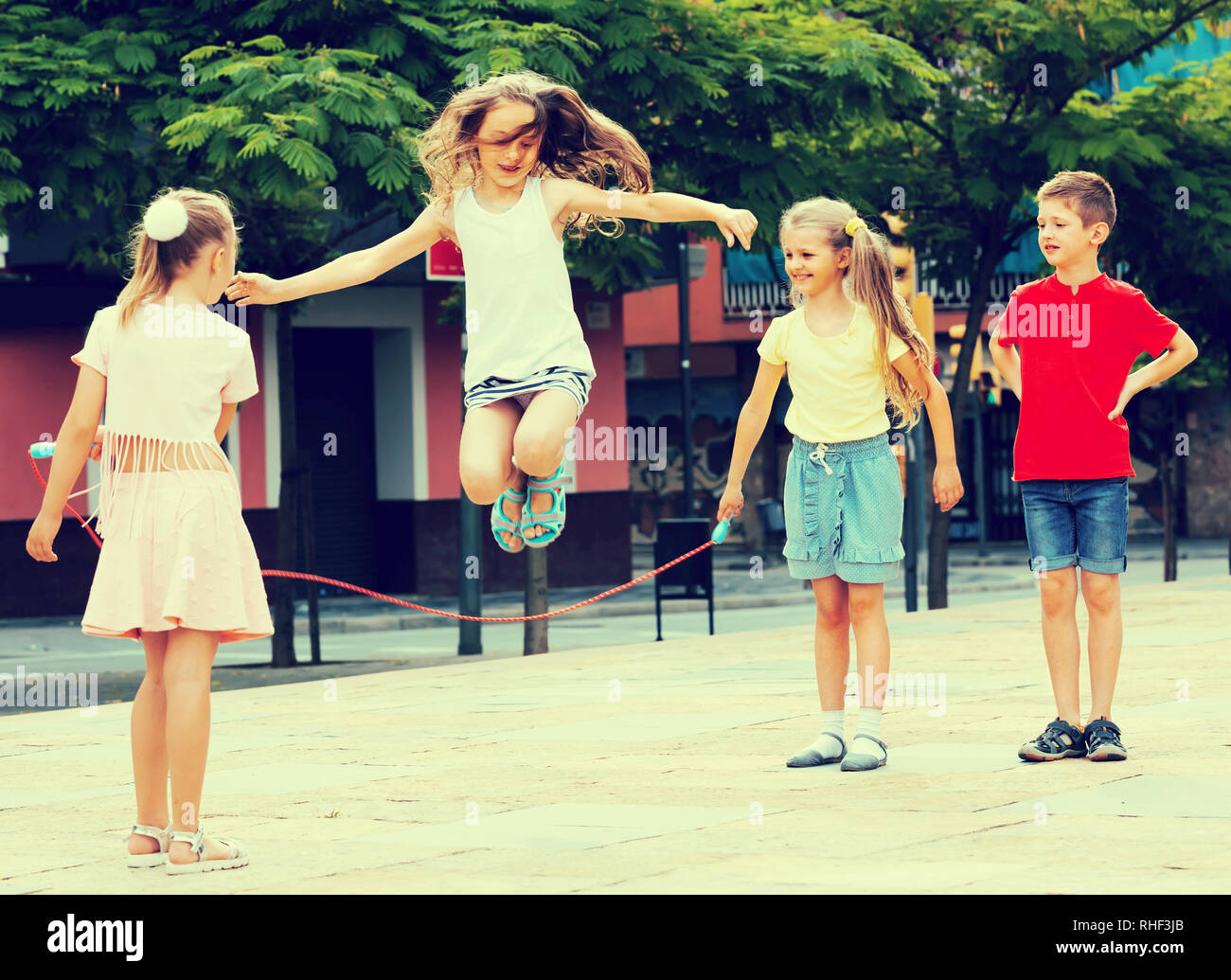 group of cheerful children skipping together with jumping rope on urban ...