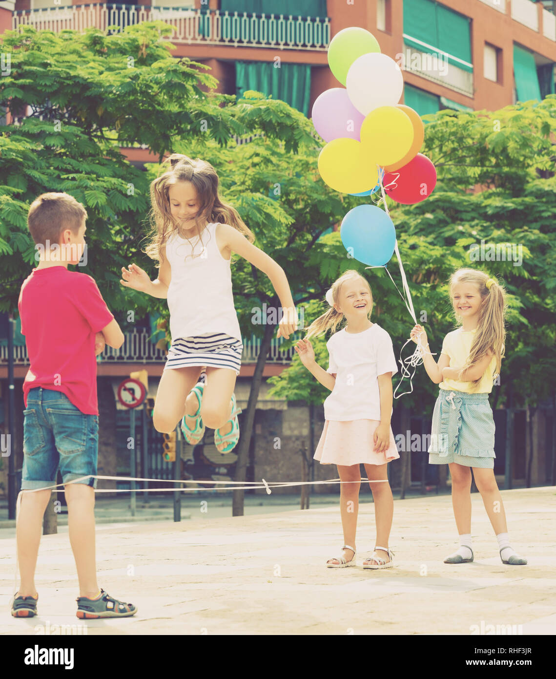 Kids skipping on jumping elastic rope in playground and hilding ...