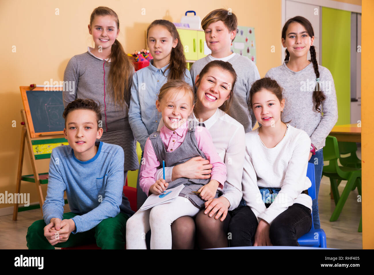 Portrait of elementary age kids with female teacher sitting in ...