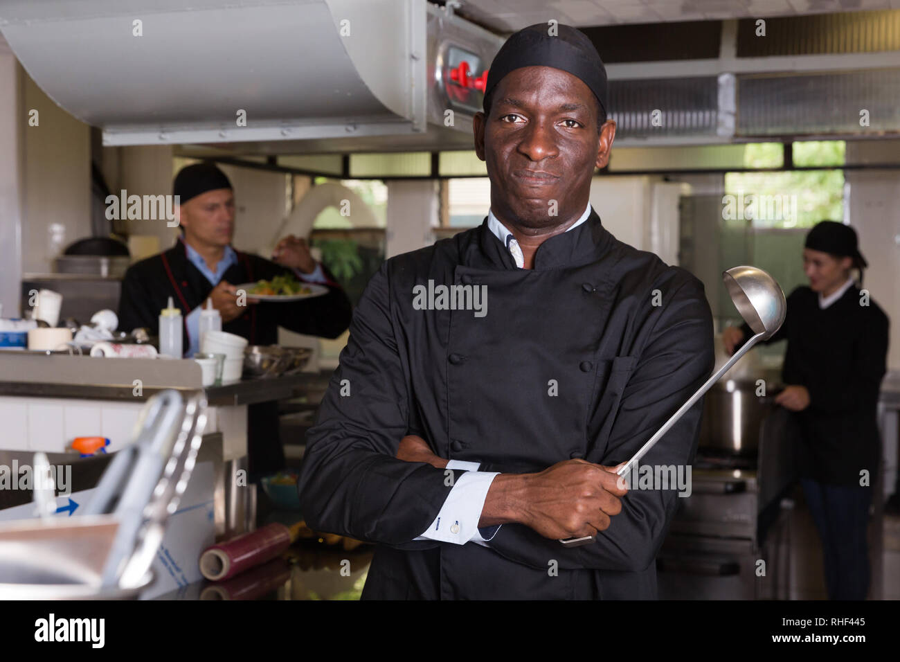 Confident African American chef of restaurant posing with arms crossed ...