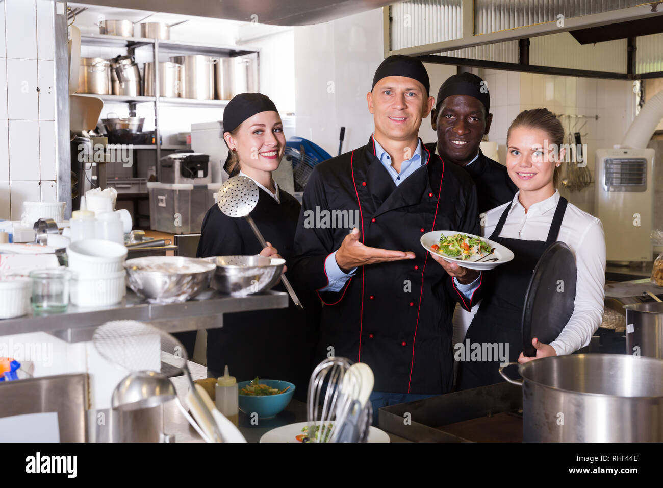 Group portrait of professional chefs posing together in modern kitchen ...