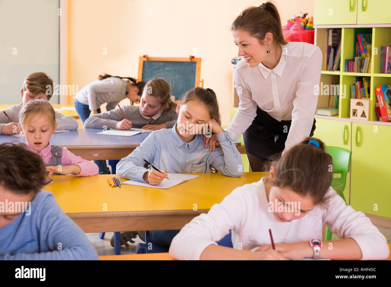 Nice teacher helping to elementary age children studying at class Stock ...
