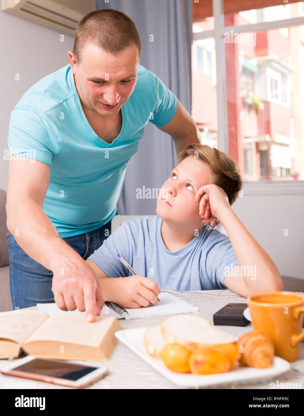 Adult male is helping his son are writing homework at the home Stock ...