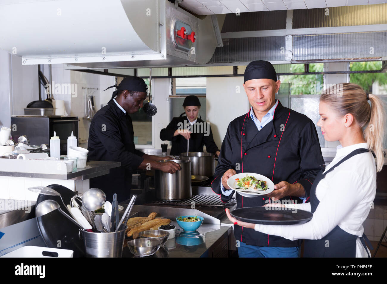 Staff of restaurant with head chef working together in kitchen Stock ...