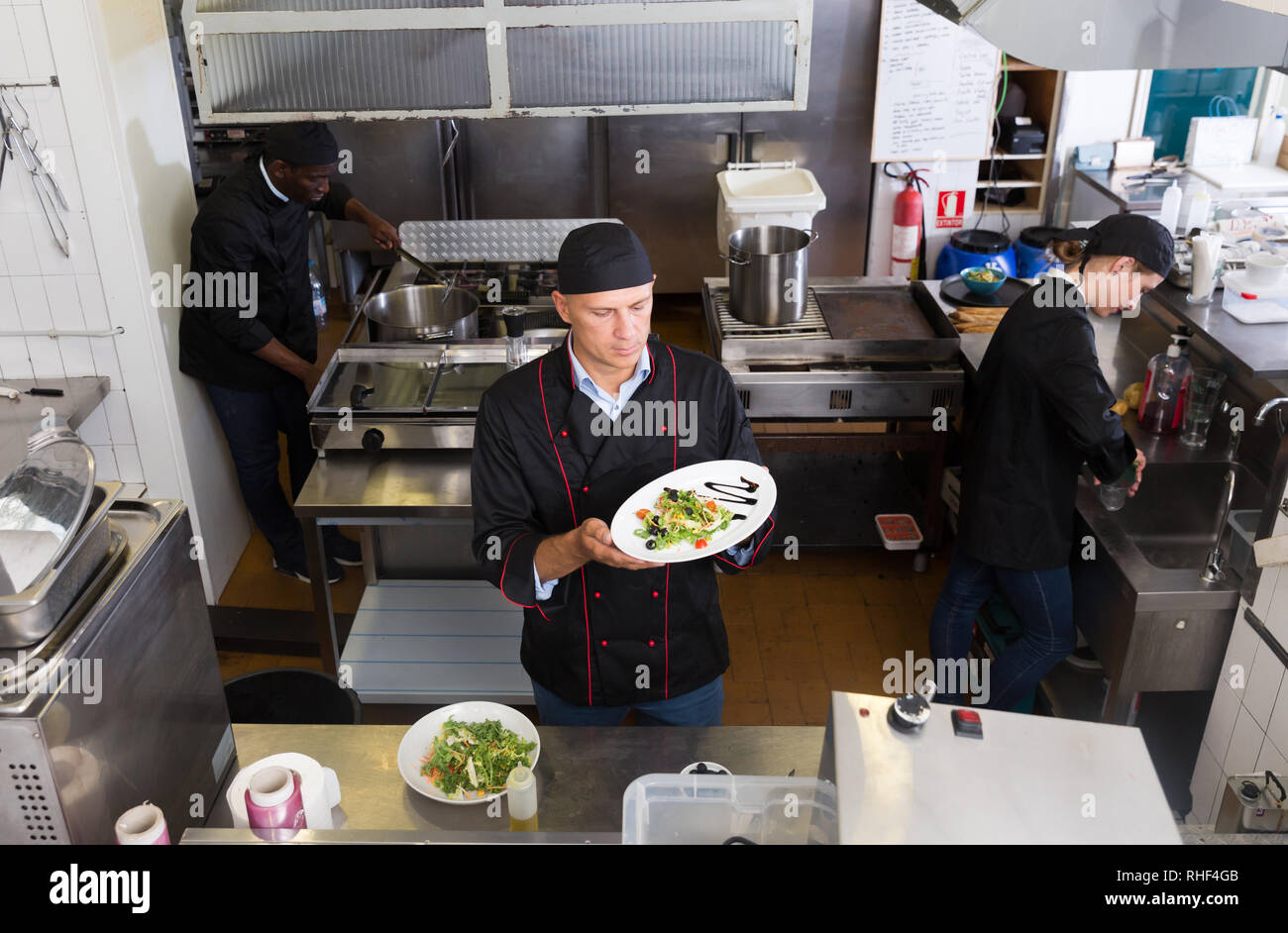 Staff of restaurant with head chef working together in kitchen Stock ...