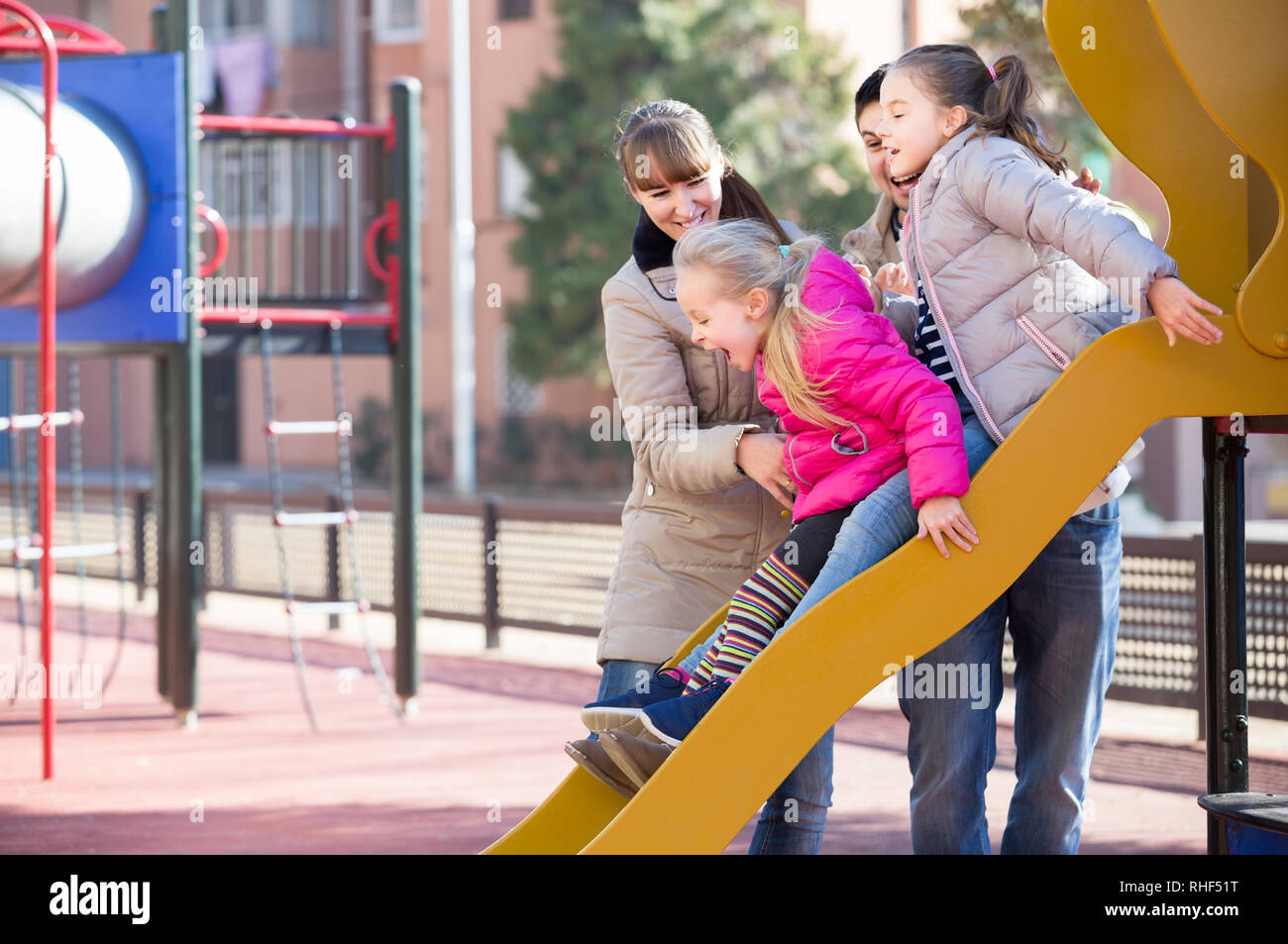 Happy russian parents playing with little daughters at slide of ...