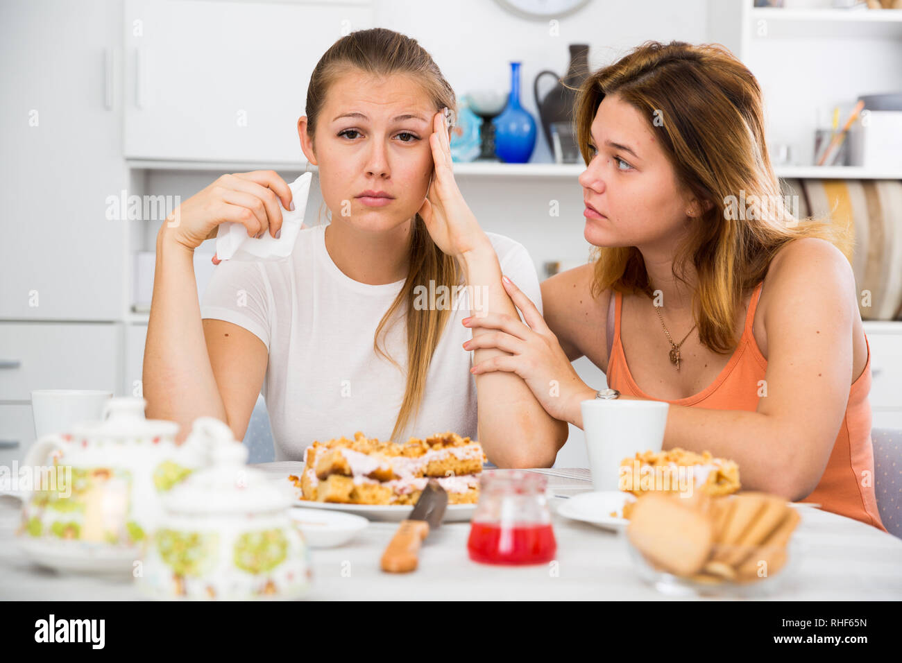 Portrait of female talking with sad girl friend at the kitchen Stock ...