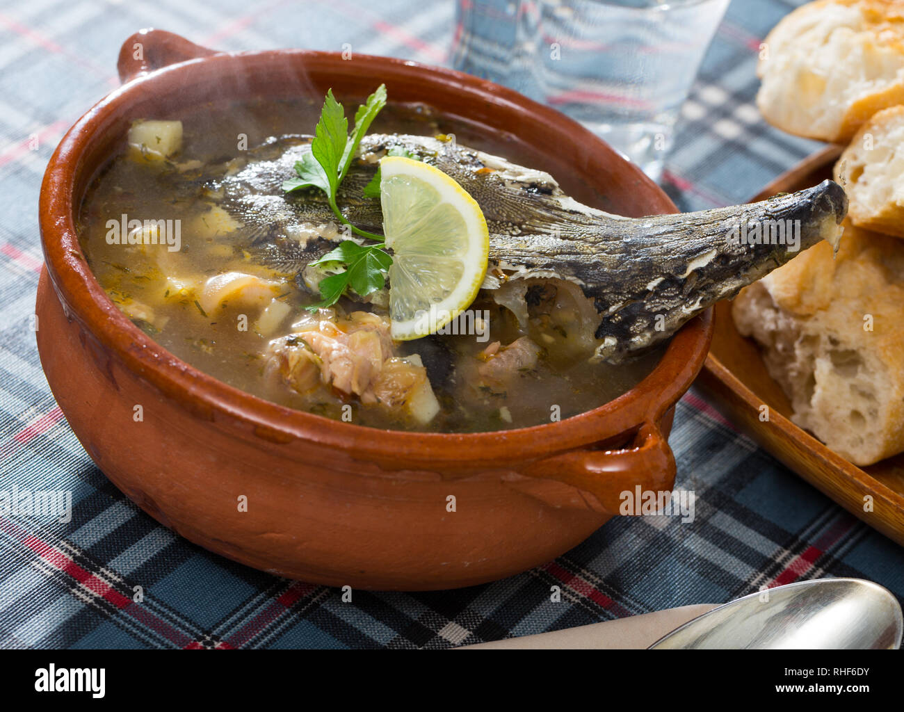 Delicious fish broth with sturgeon served in clayware with greens and ...