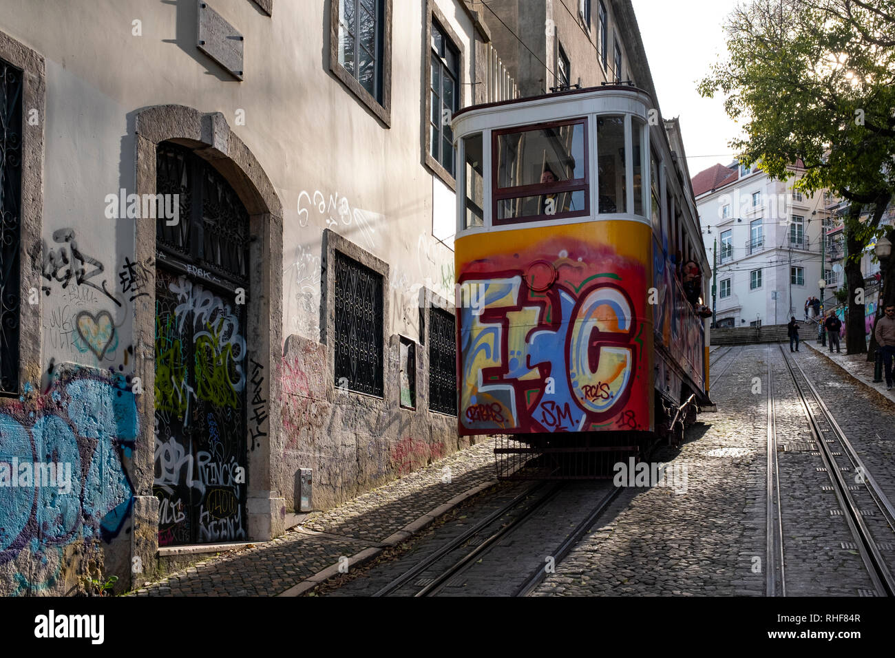 Lisbon Trams descending down a steep slope next to traditional houses ...