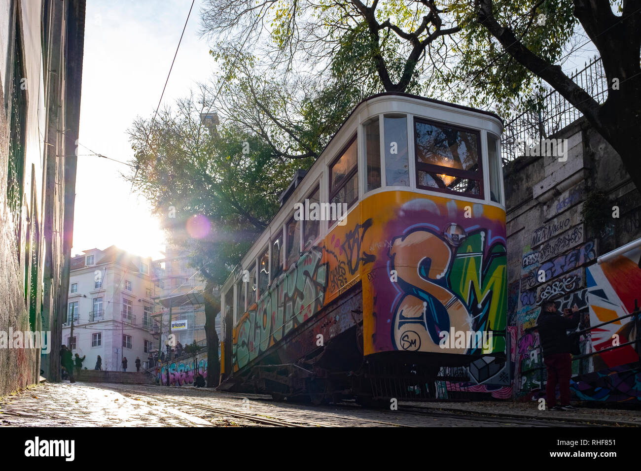 Lisbon Trams descending down a steep slope next to traditional houses ...