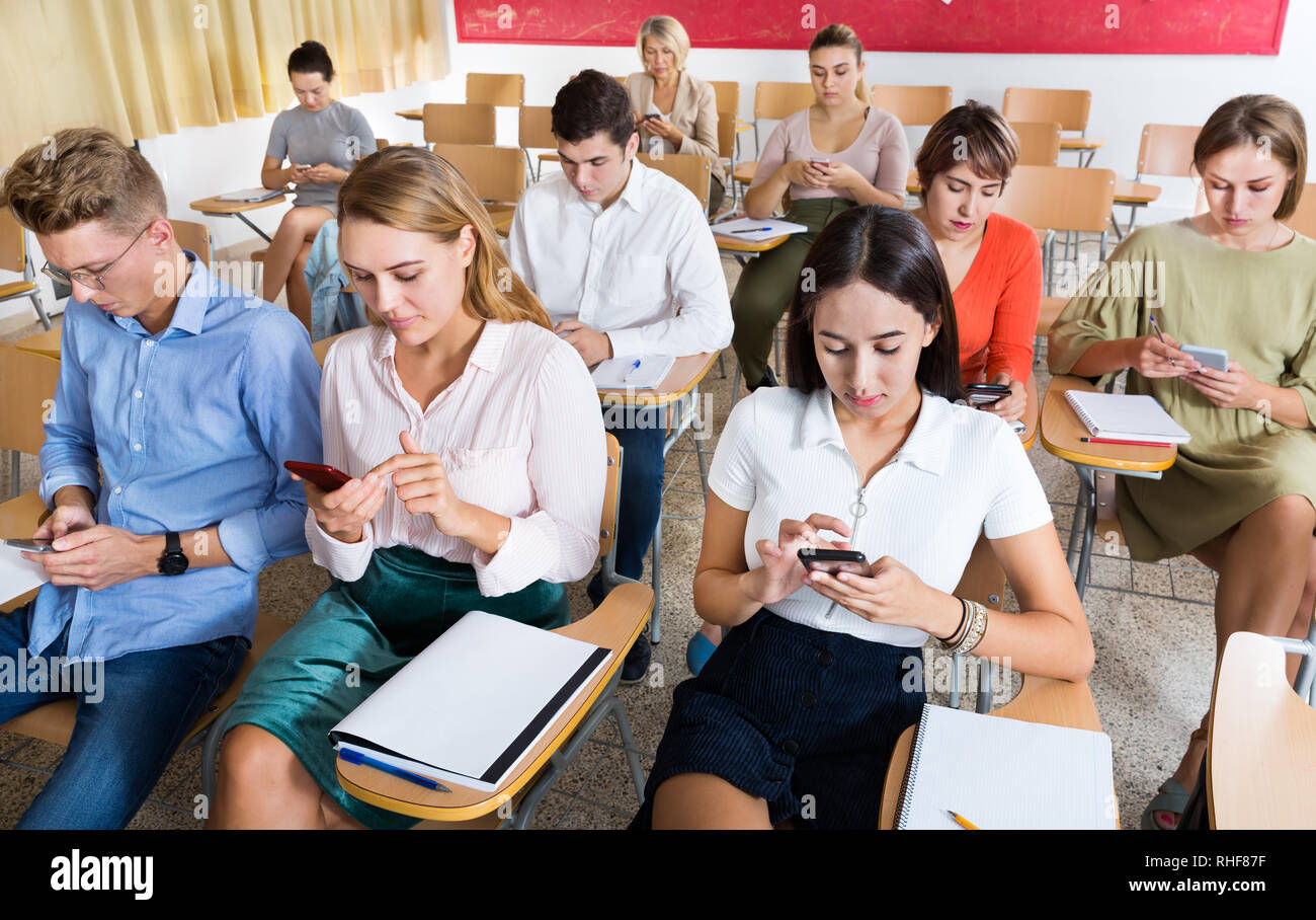Group of modern people sitting with mobile phones on lecture in a ...