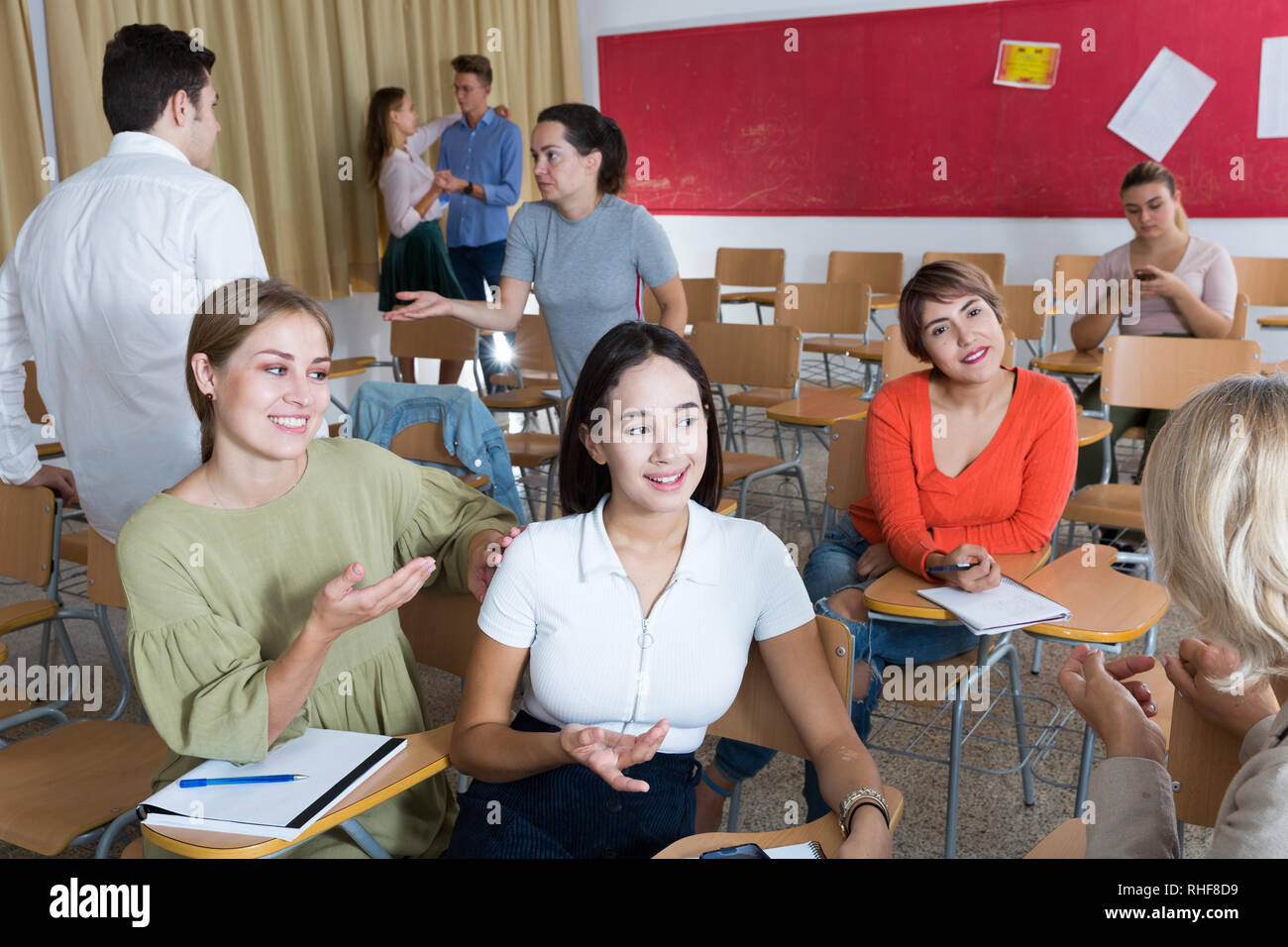 Friendly student group talking in classroom having break between ...