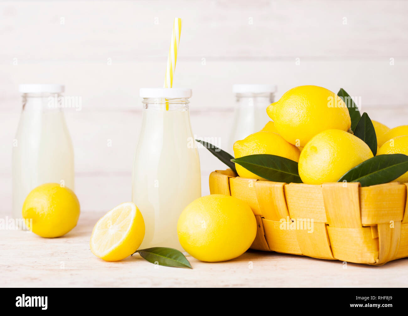 Glass bottles of organic fresh lemon juice with raw lemons in bamboo ...