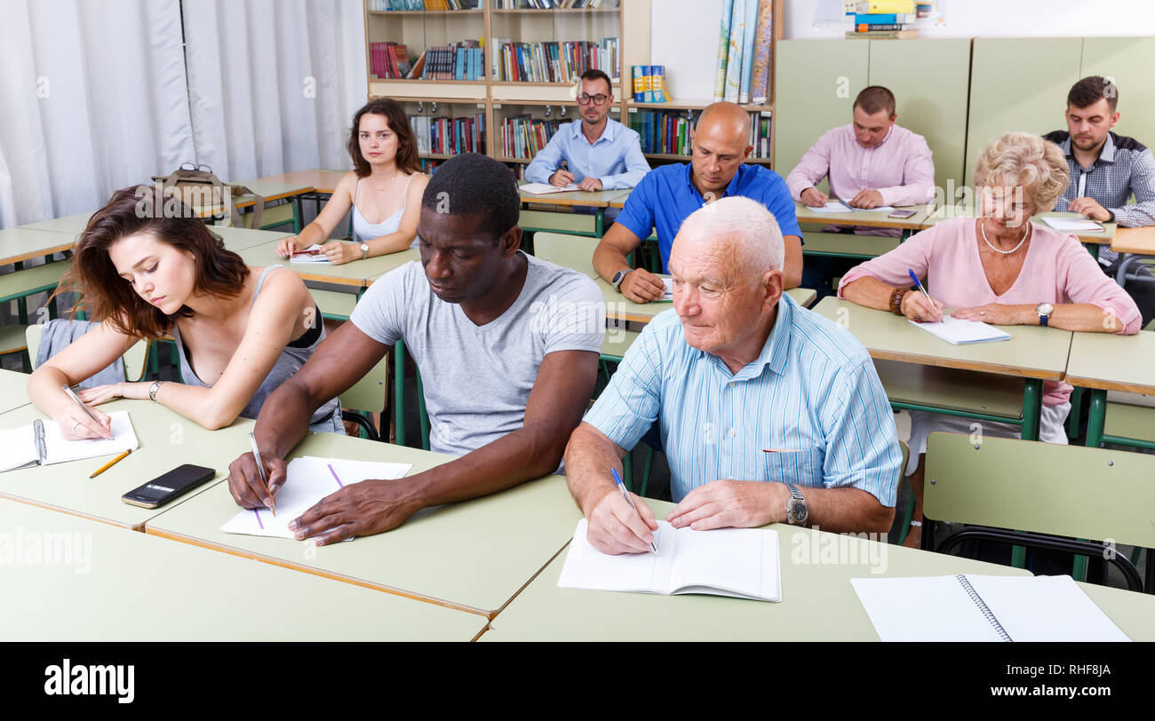 Students mixed age take a written exam in the classroom Stock Photo - Alamy