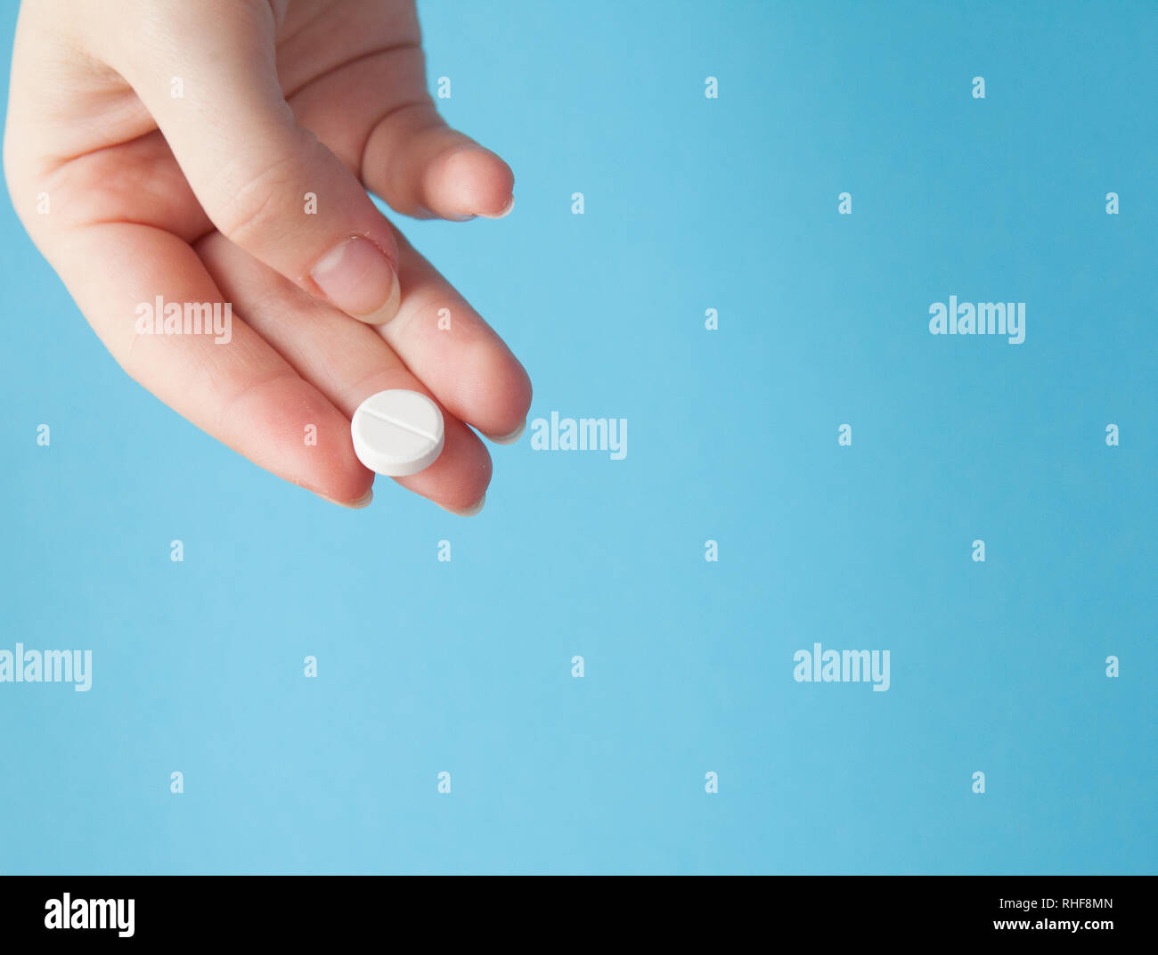 Close-up shot of pill in nurse's hand isolated over blue background ...