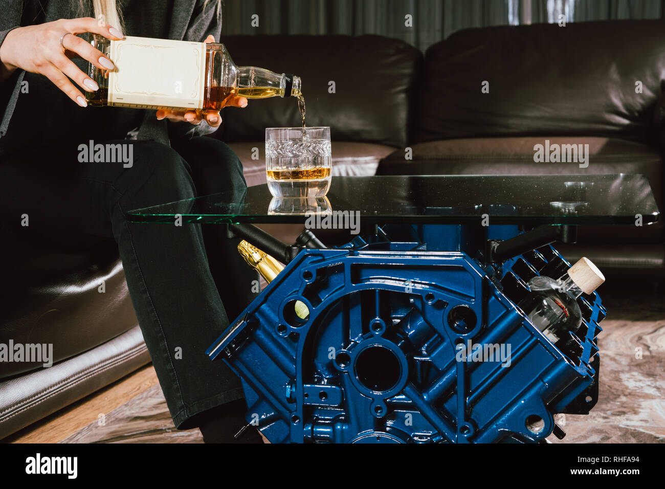 Young caucasian blonde girl sitting on sofa with glass of whiskey at ...