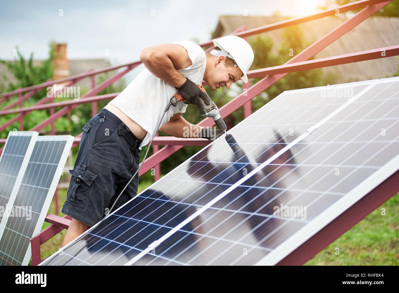 Back view of young technician in helmet connecting solar photo voltaic ...