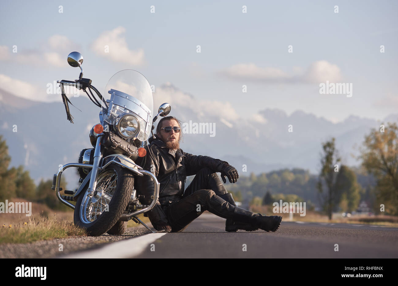 Handsome motorcyclist in black leather clothing sitting at modern ...
