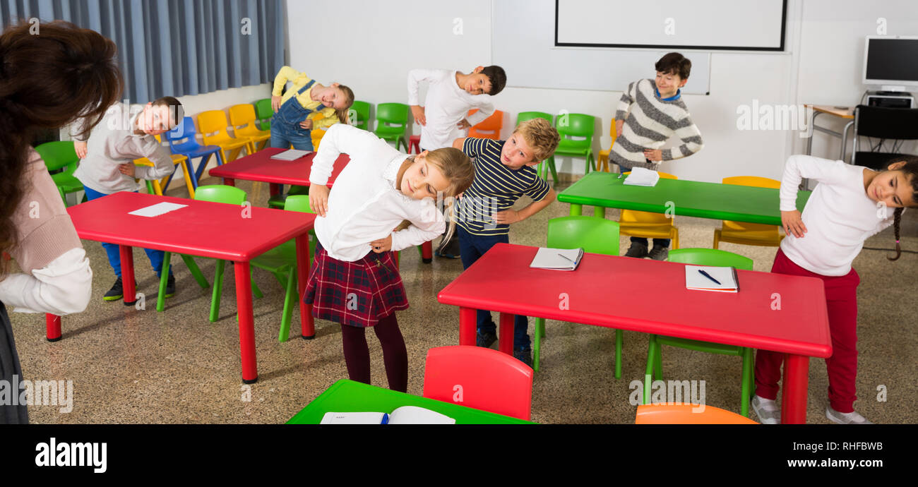 Portrait of schoolchildren with teacher performing daily physical ...