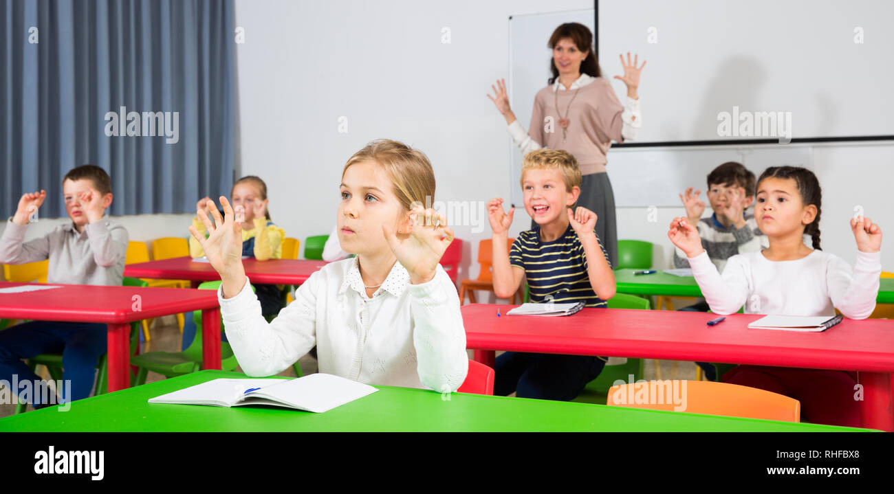 Portrait of schoolchildren with teacher performing daily physical ...