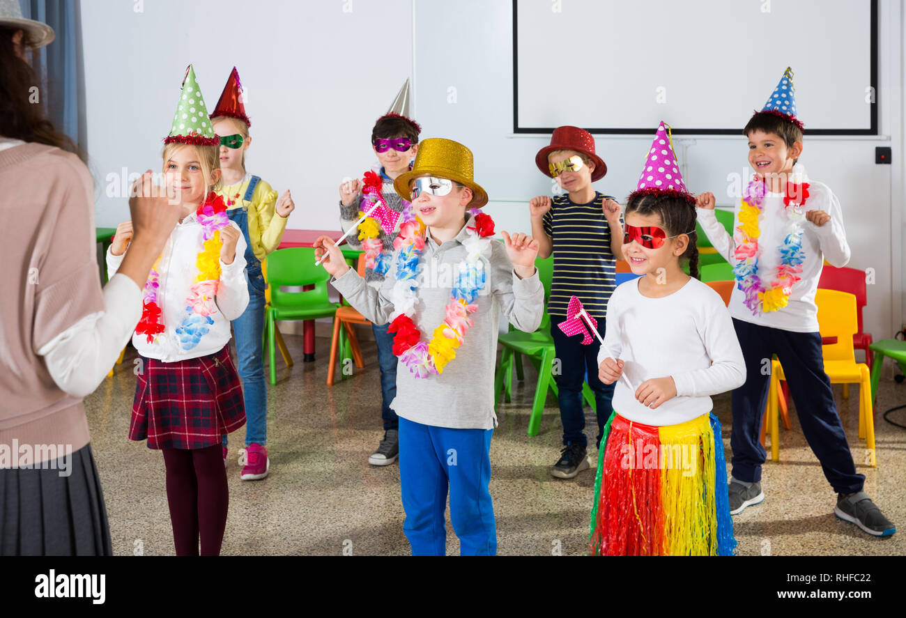 Group of cheerful school kids wearing festive hats having fun with ...
