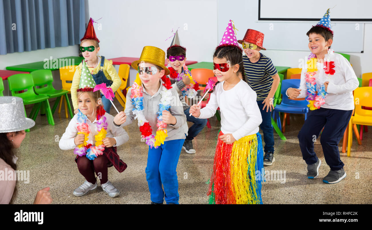 Group of cheerful school kids wearing festive hats having fun with ...