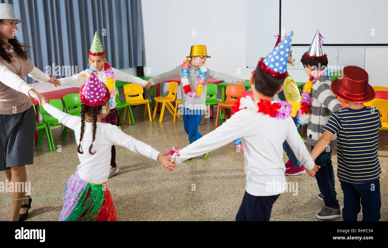 Group of cheerful school kids wearing festive hats having fun with ...