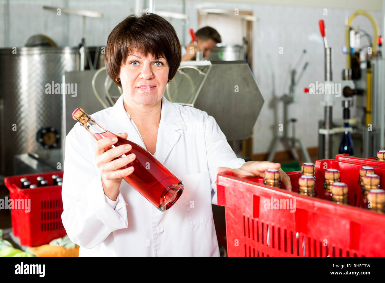 Beautiful female worker sorting wine bottles at sparkling wine factory ...
