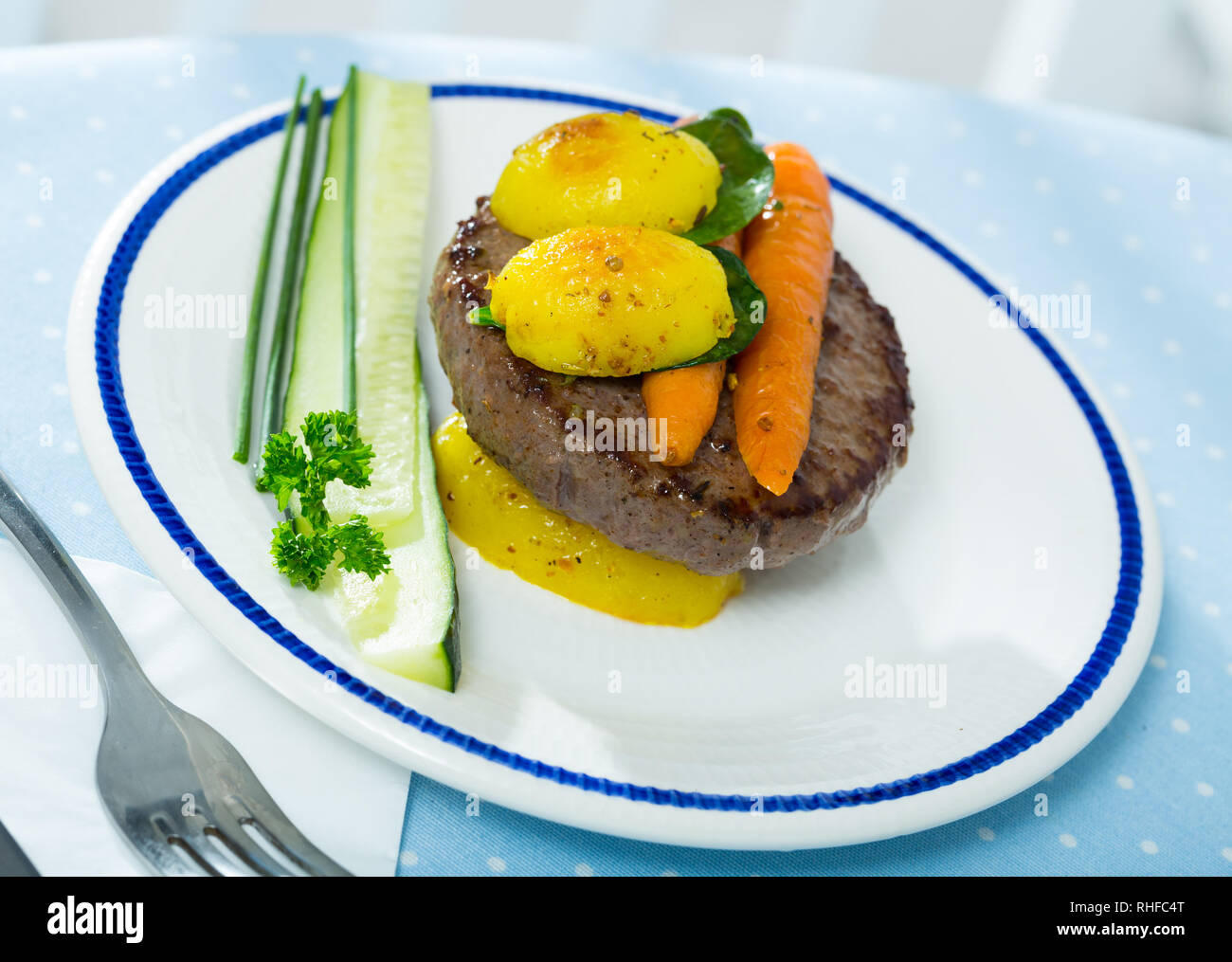 Beef patty served with baked new potatoes and carrots Stock Photo - Alamy