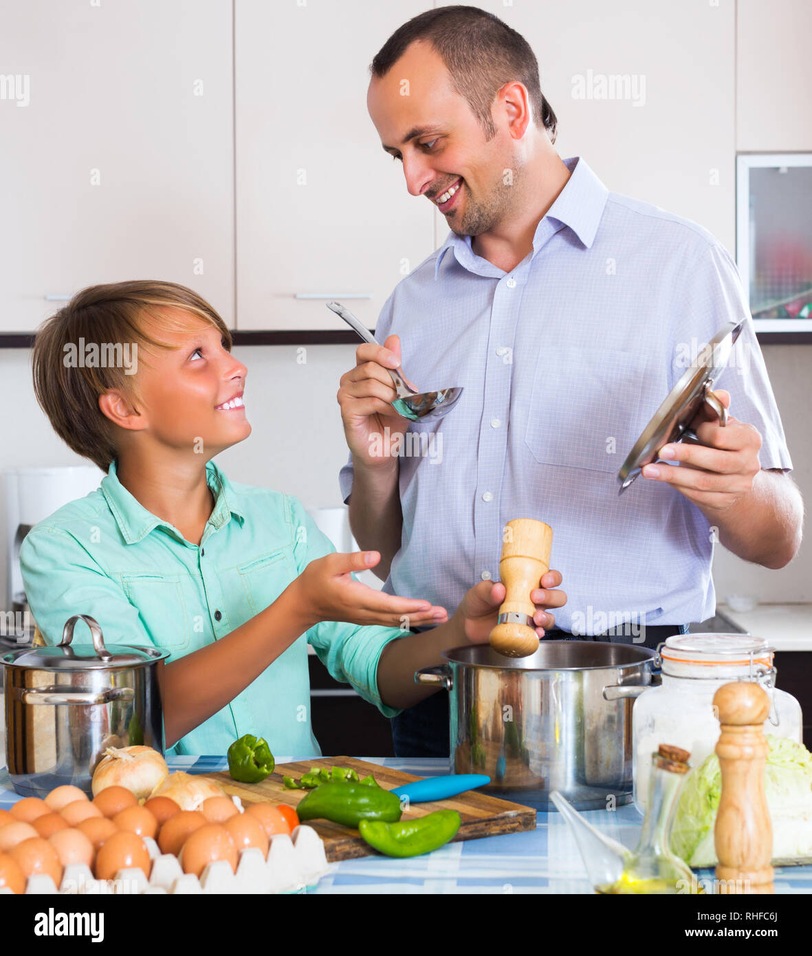 Happy man and smiling teenager cooking together at kitchen Stock Photo ...